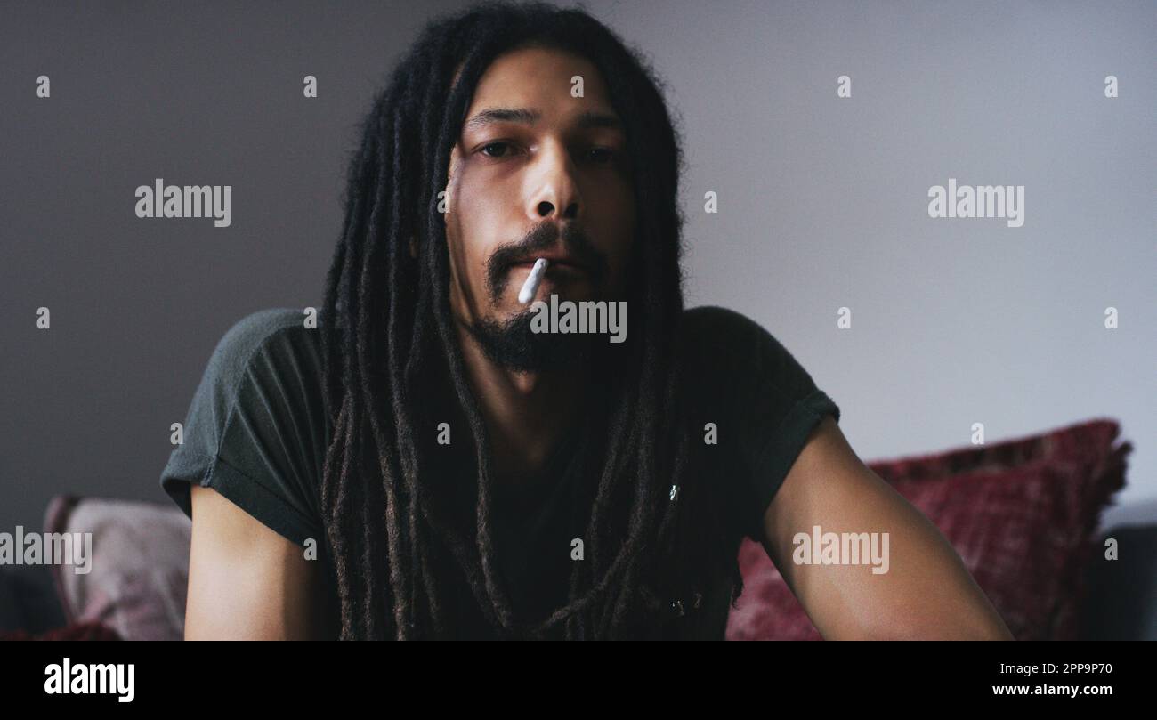 Living the high life. a young man smoking a marijuana joint at home ...