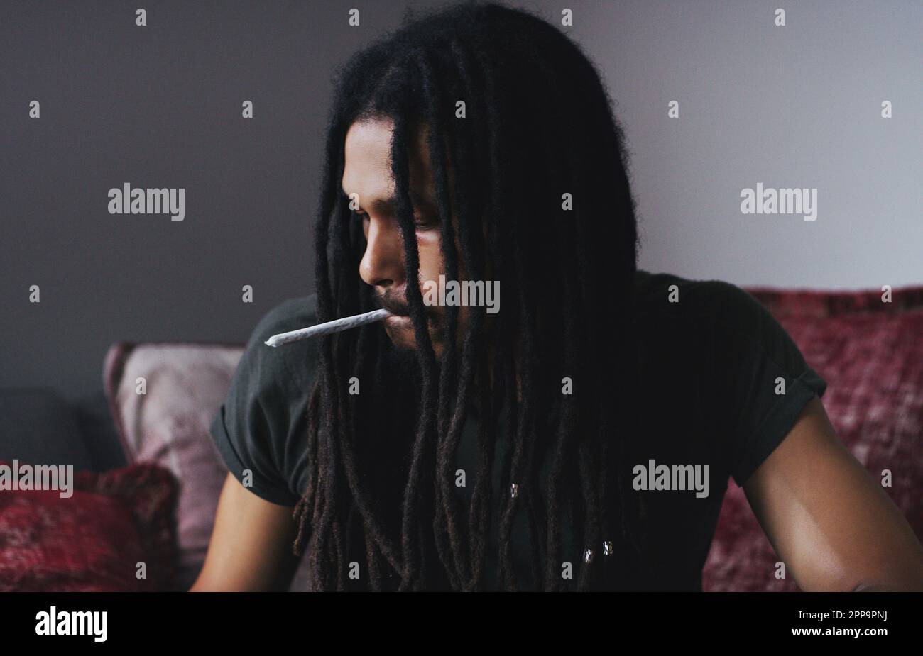 Smoking in solitude. a young man smoking a marijuana joint at home ...