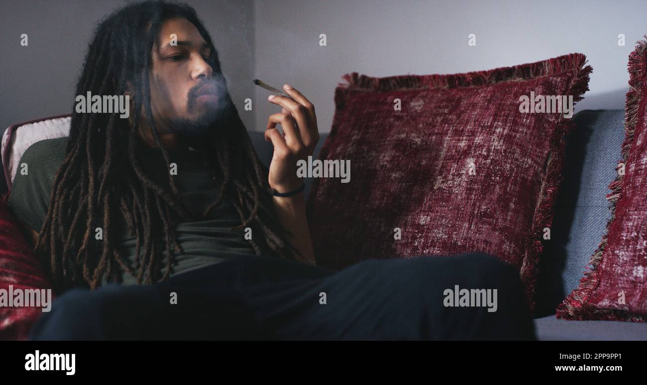 Getting high at home. a young man smoking a marijuana joint at home ...