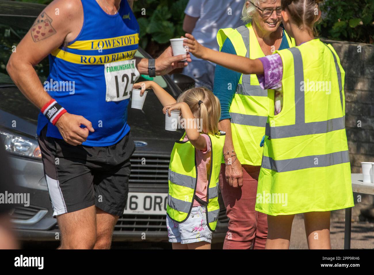 At a 10k road race helpers hold out plastic cups of water for the ...
