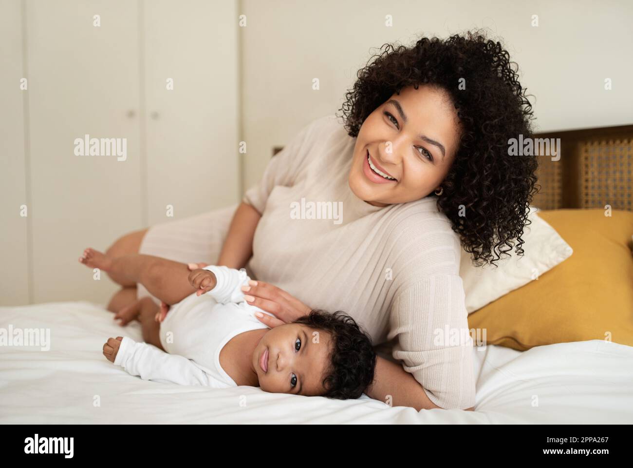 Glad young african american lady plus size and little child lie on bed ...