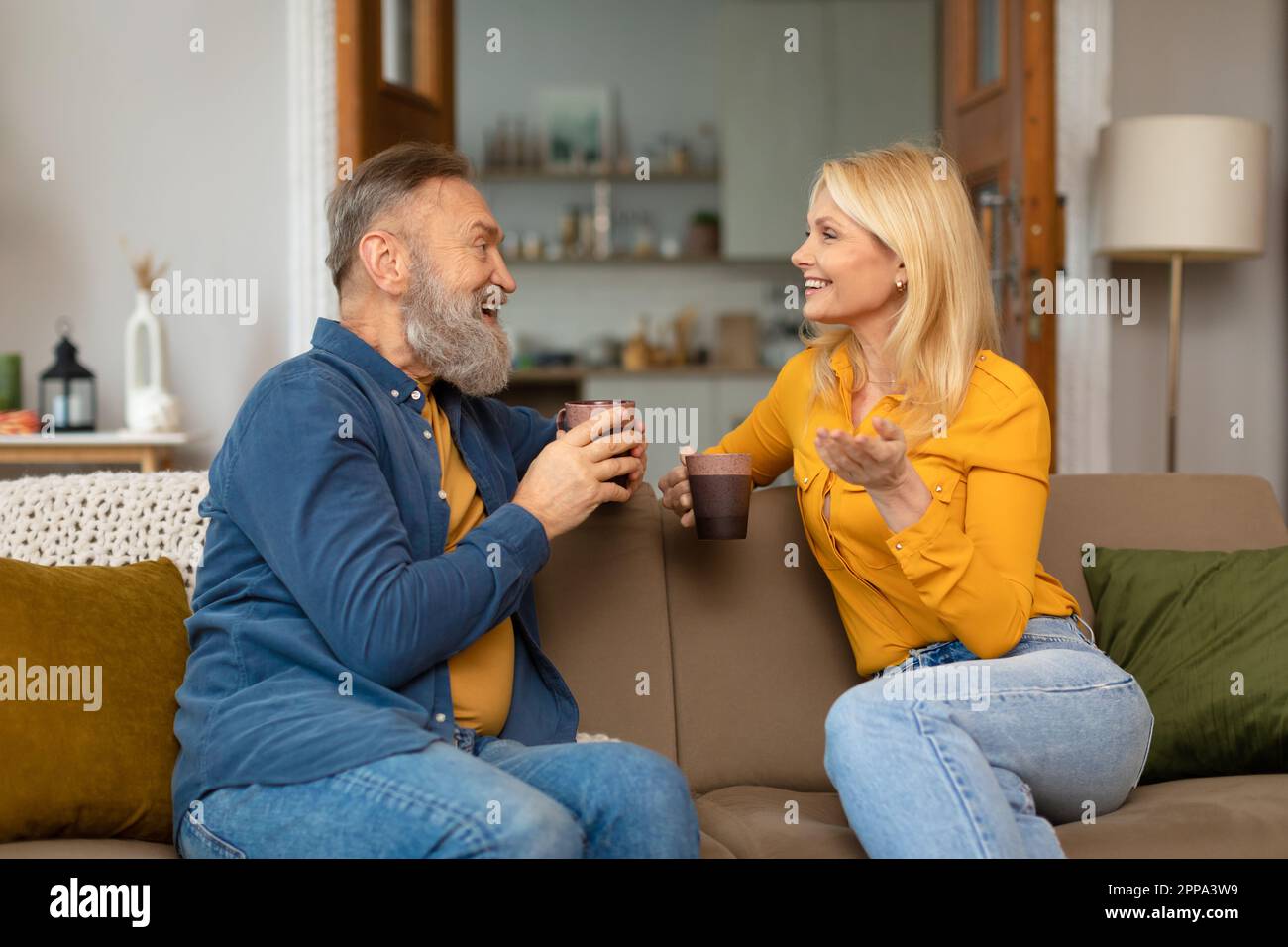 Senior Couple Drinking Coffee Sitting On Sofa Talking At Home Stock ...