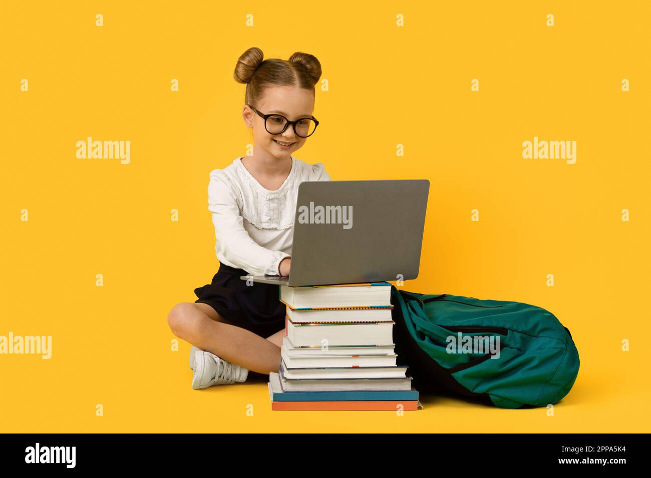 Cute Little Schoolgirl Doing Homework On Laptop Over Yellow Background ...