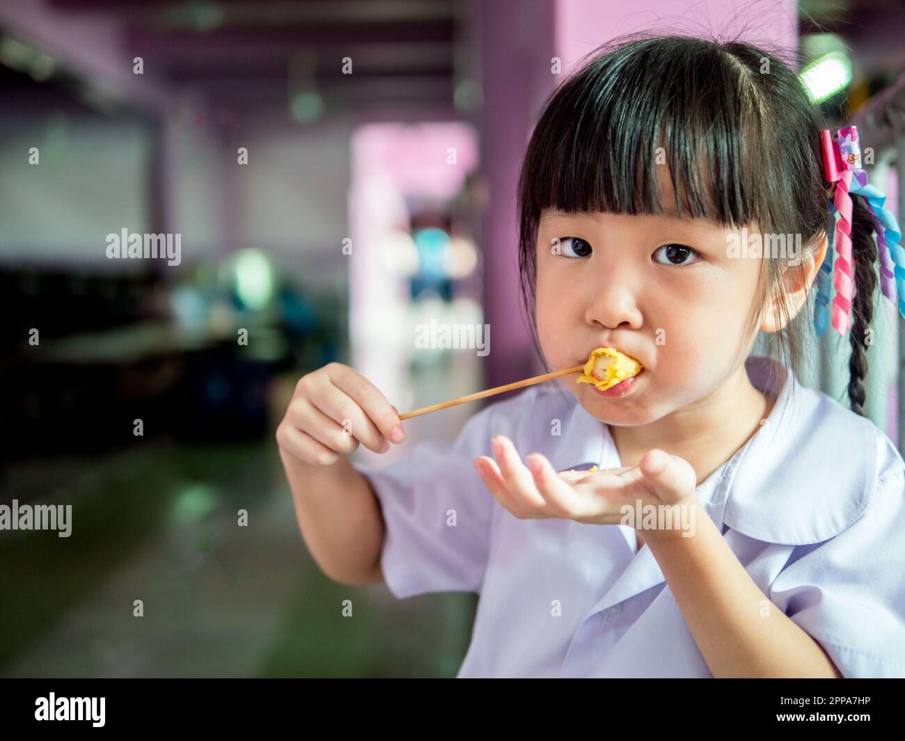 Asian girl child eating a crispy wonton Stock Photo - Alamy