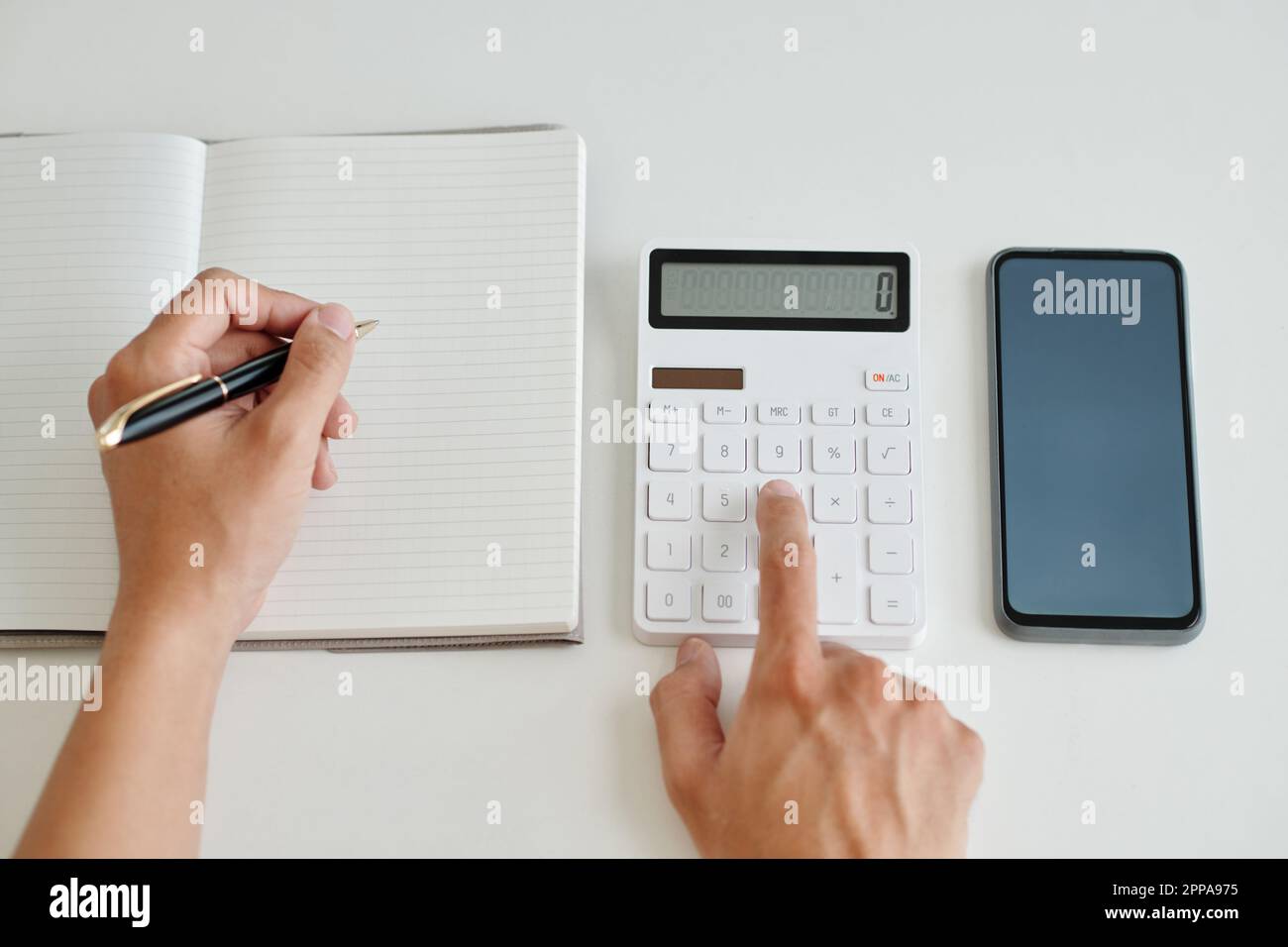 Hands of entrepreneur making calculations and writing in planner Stock ...