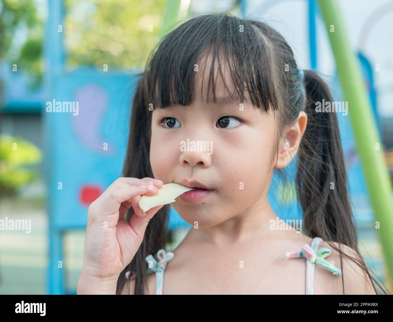 asian baby child playing on playground, eating mango Stock Photo - Alamy