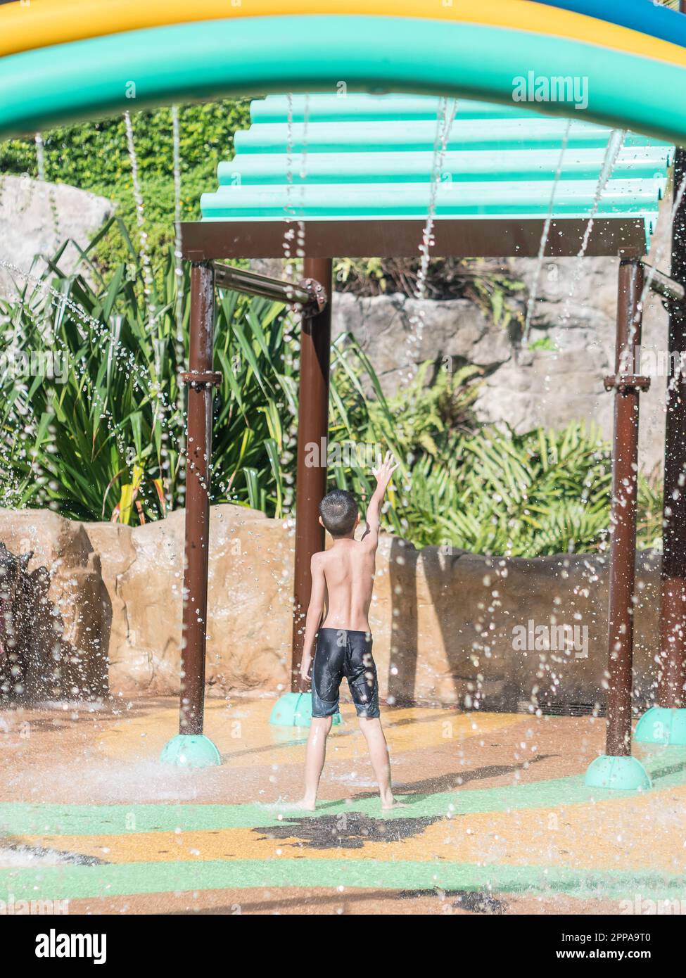 Asian child little boy having fun to play with water in park fountain ...