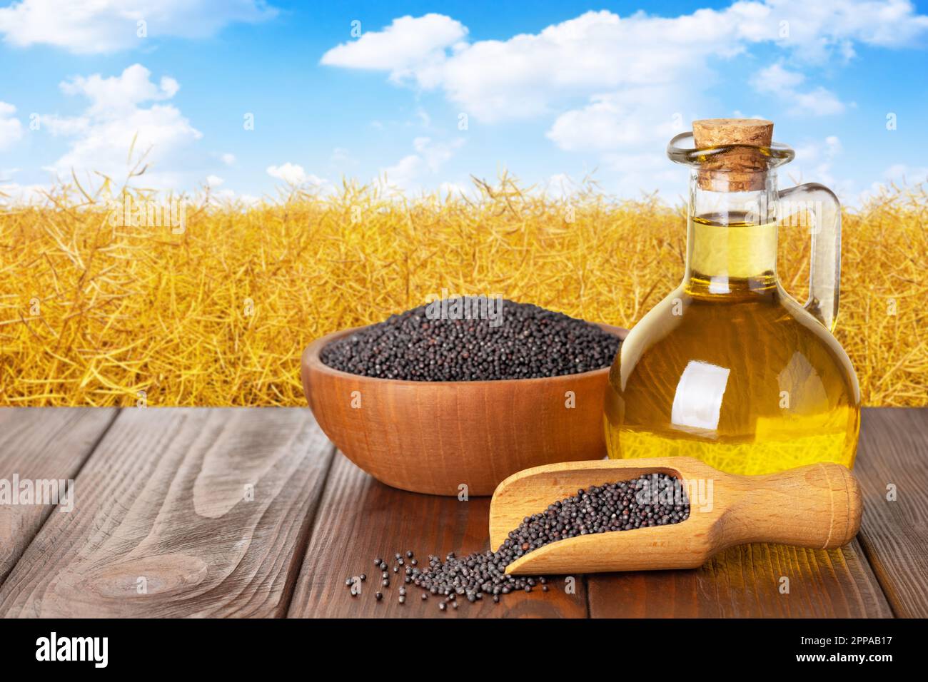 rapeseed oil in bottle with dry rape seeds in bowl on table and ...