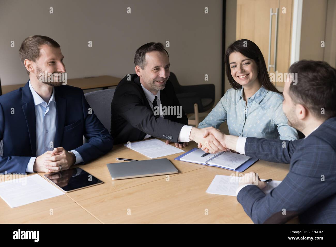 Positive middle aged business partners giving handshakes over meeting table Stock Photo - Alamy