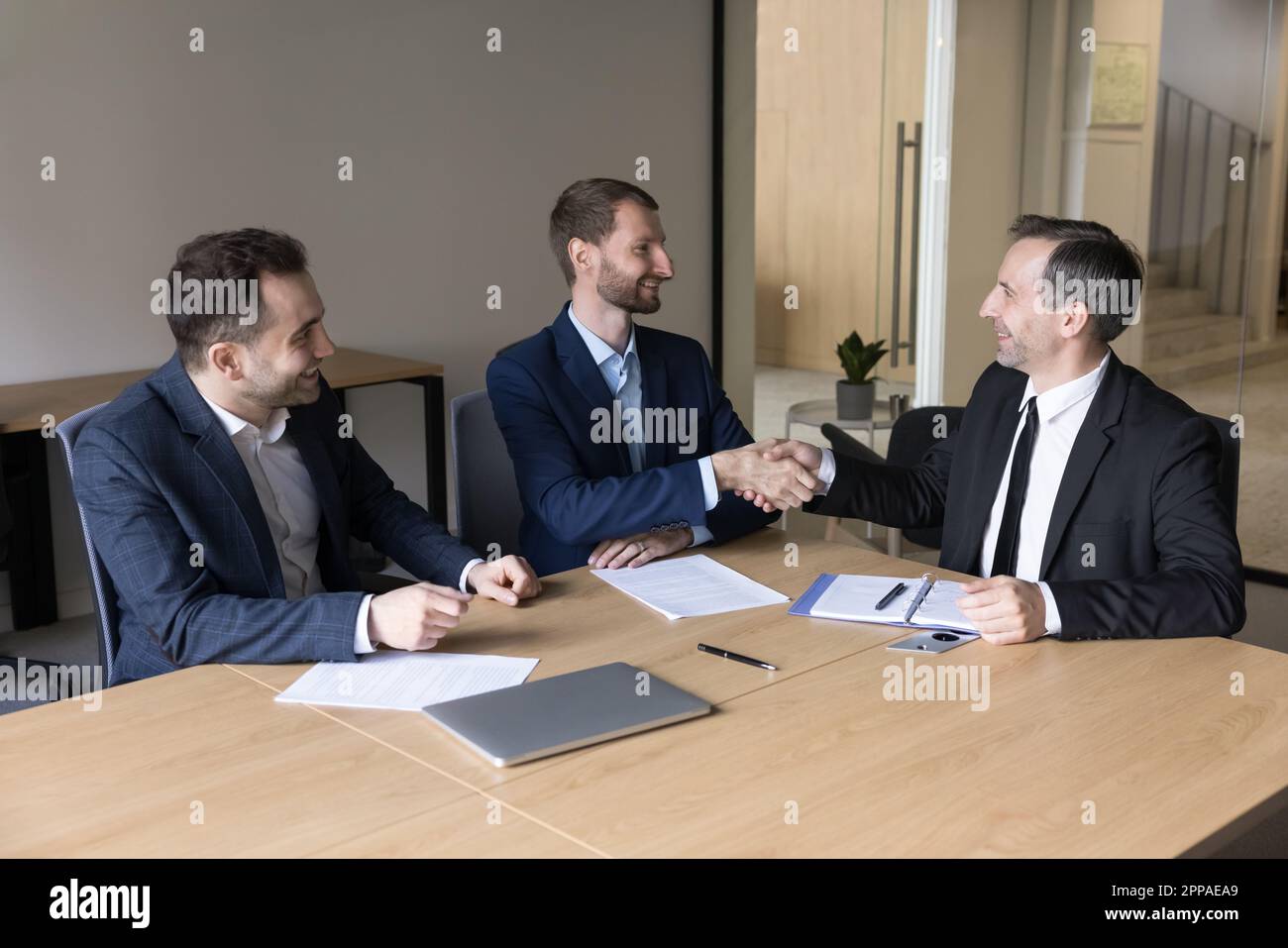 Happy confident business partners shaking hands after successful ...