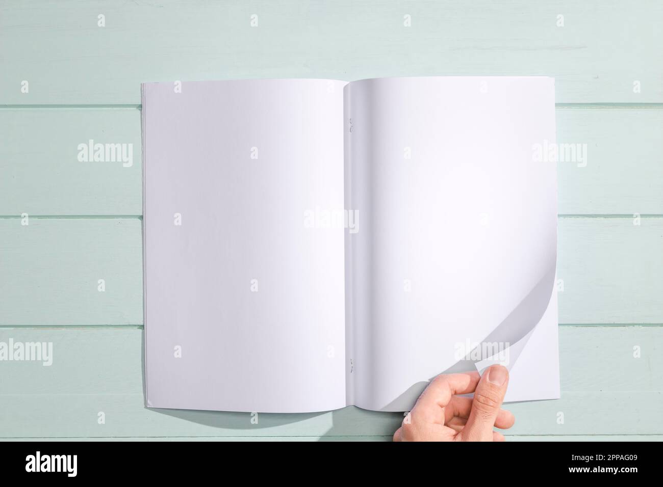 Hand turning white page top view Stock Photo - Alamy