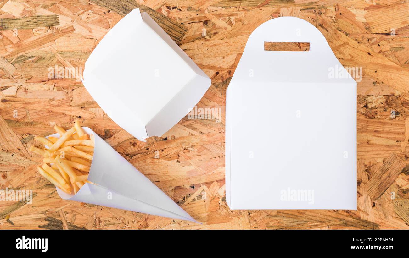French fries paper cone white package wooden background Stock Photo - Alamy