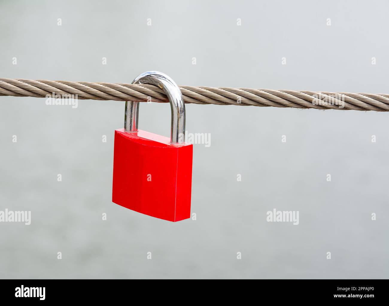 Closeup of a red padlock hanging on a steel cable Stock Photo - Alamy
