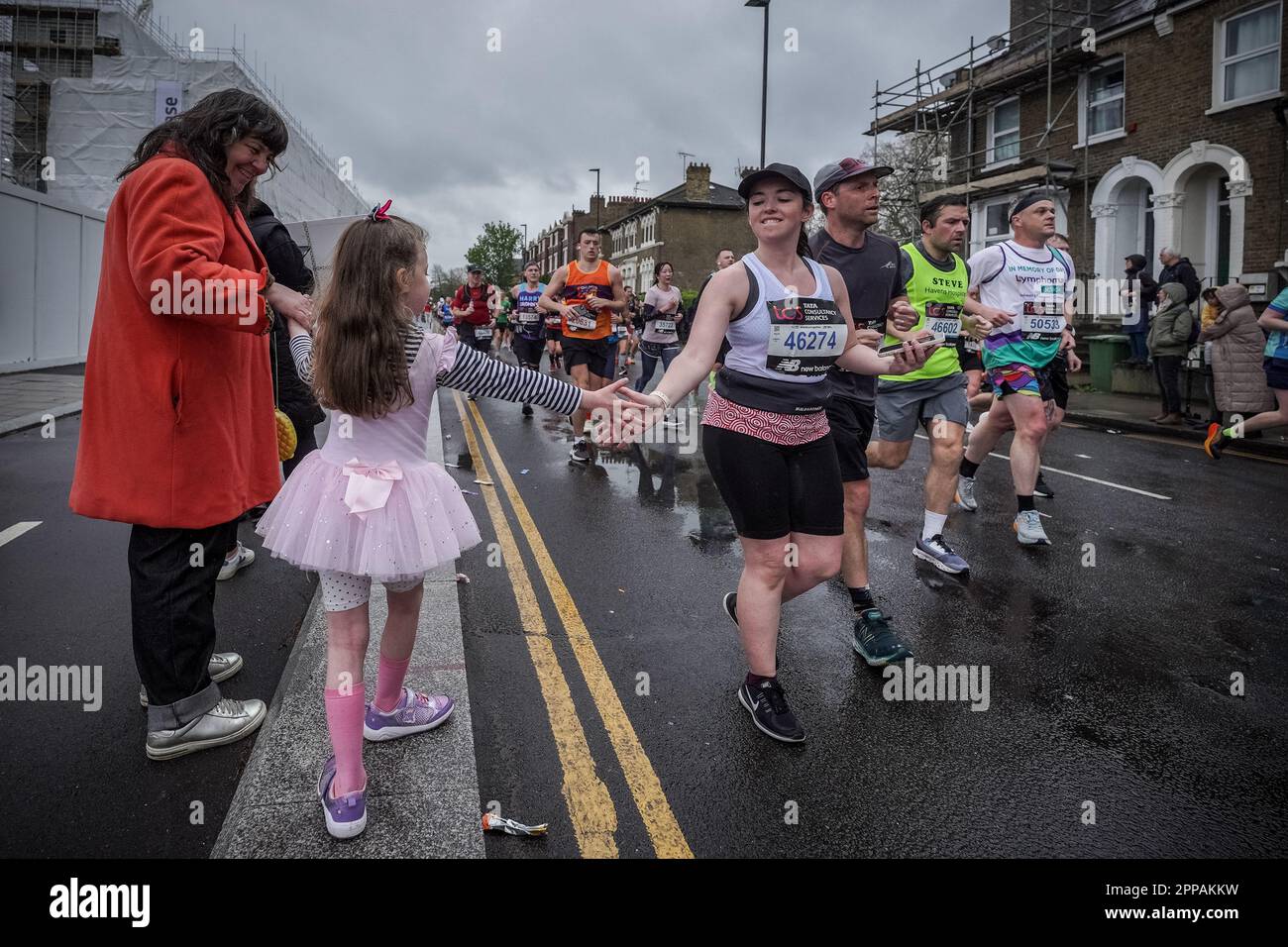 London, UK. 23rd April, 2023. A local girl offers supports to runners ...
