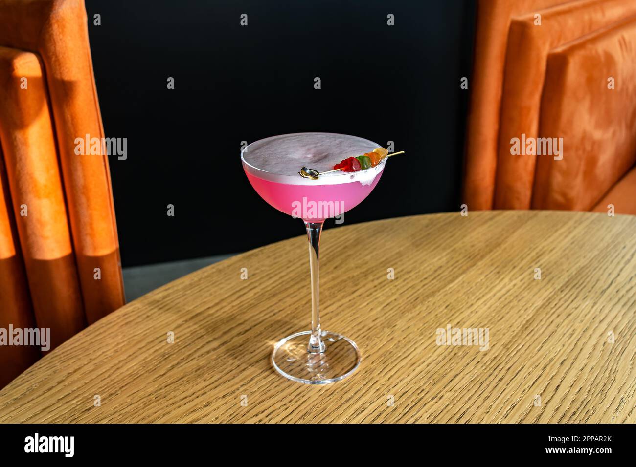 Shiny cocktail glass with fresh pink alcohol drink and jelly bears ...