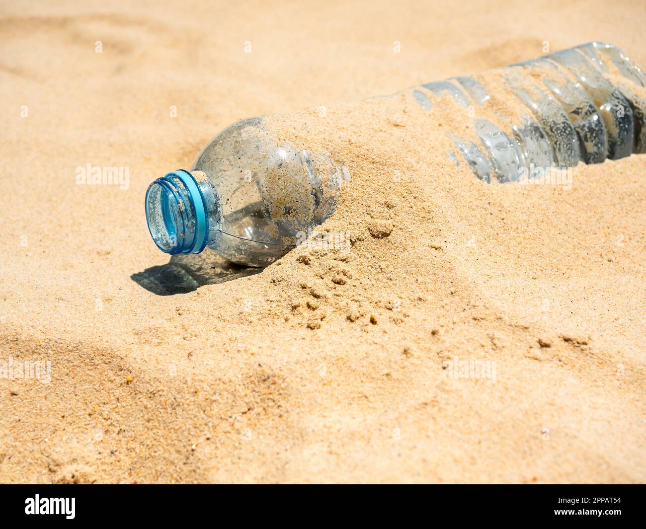 Plastic bottle on sandy beach. Close-up empty uncapped used plastic ...