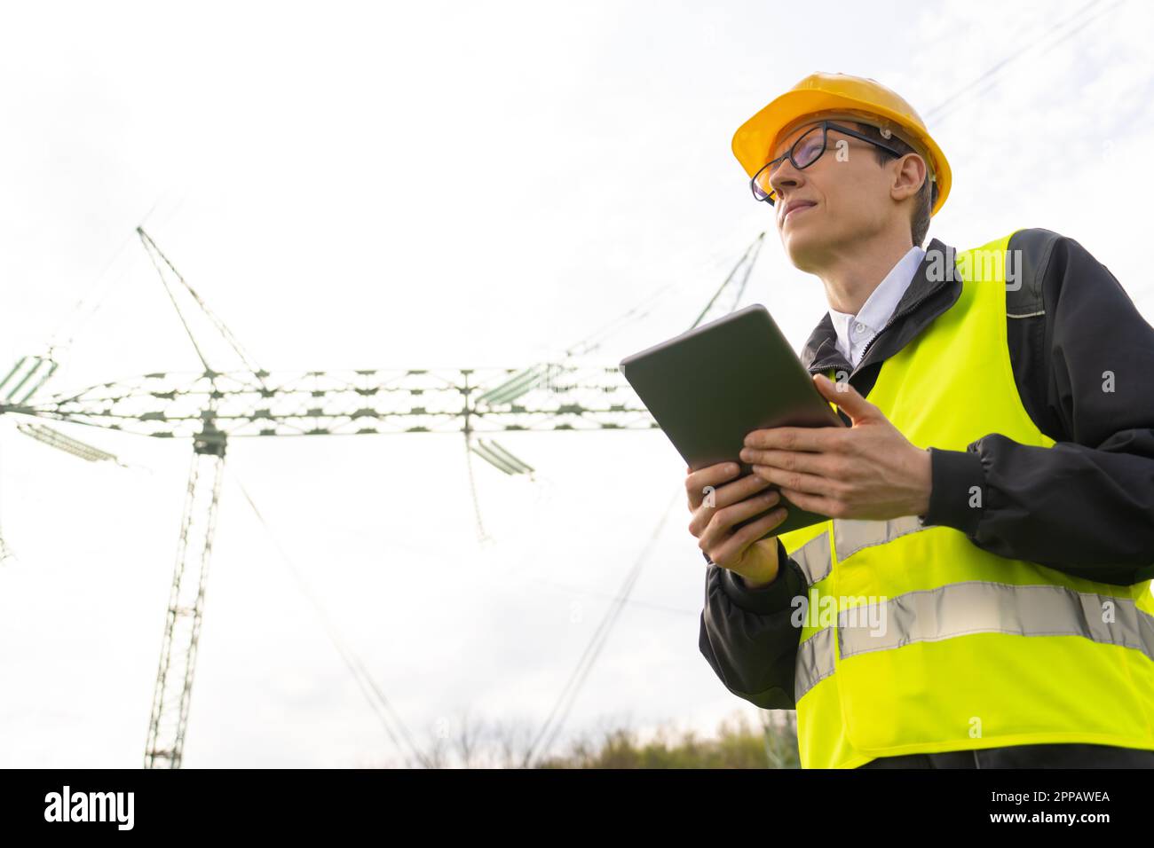 Engineer with digital tablet on a background of power line tower. High ...