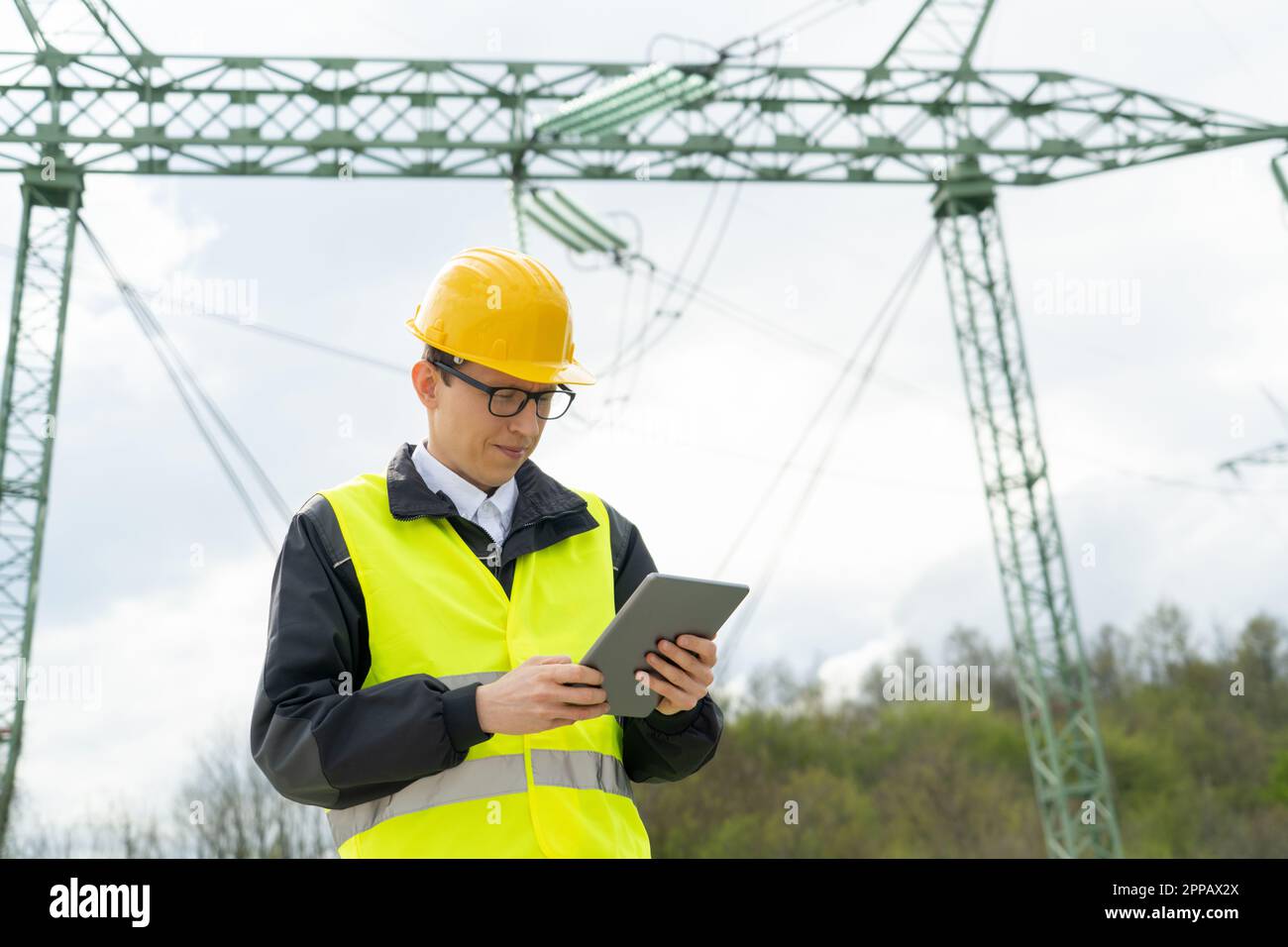 Engineer with digital tablet on a background of power line tower. High ...