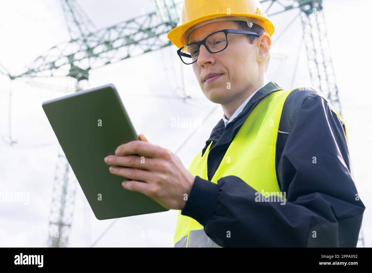 Engineer with digital tablet on a background of power line tower. High ...