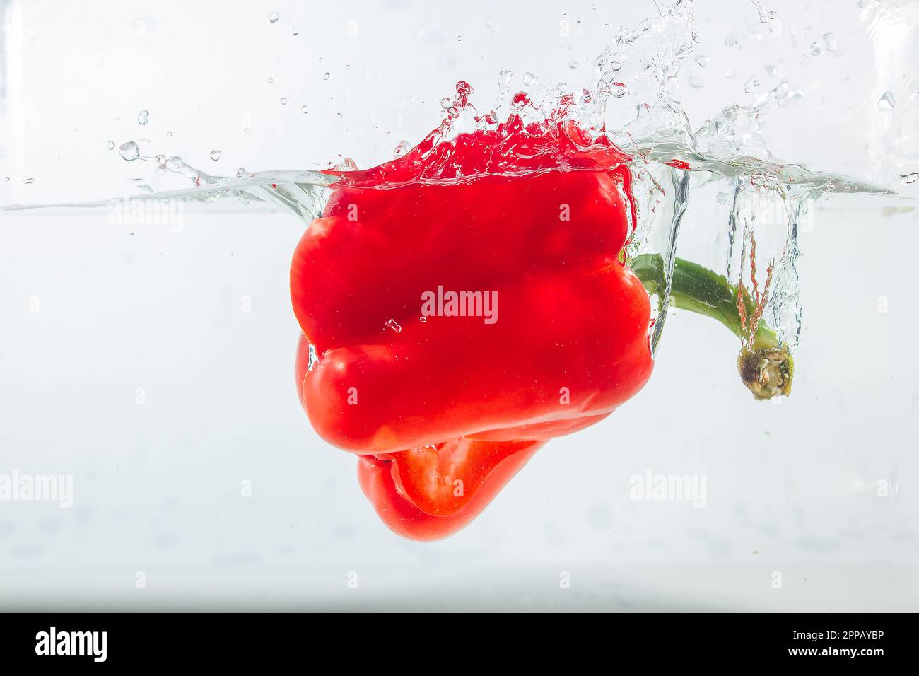 Sweet pepper in water splashes, red sweet pepper on a white background ...