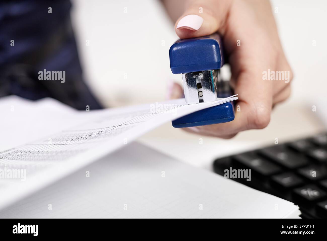 Office worker staples documents at office desk Stock Photo - Alamy