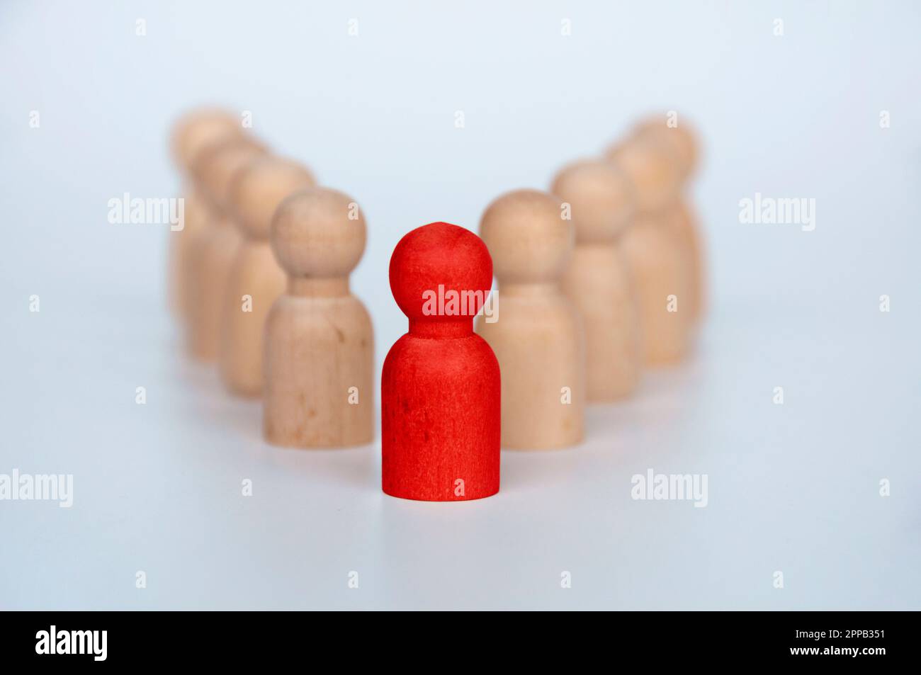 Red wooden figure representing a leader leading other figure ...