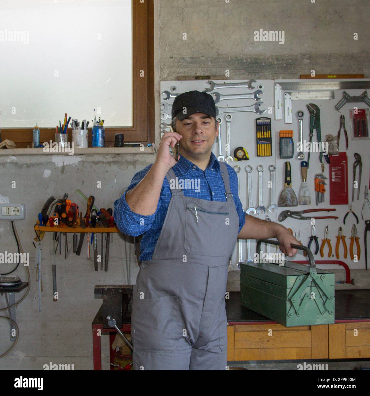 image of a mechanic in his workshop, while talking on the phone for a ...