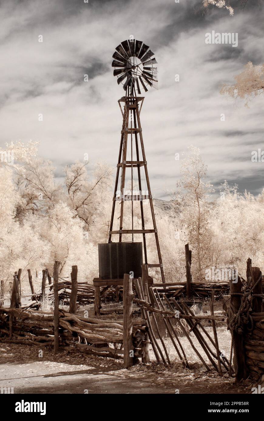 Windmill and water storage tank by a desert corral Stock Photo - Alamy