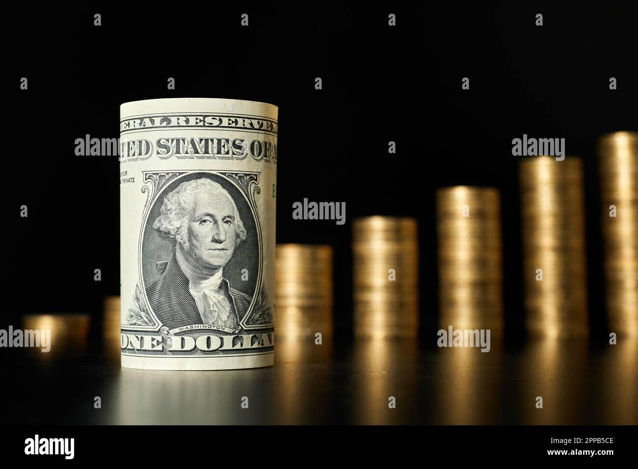 Rolled one dollar bill on the background of stacks of coins Stock Photo ...