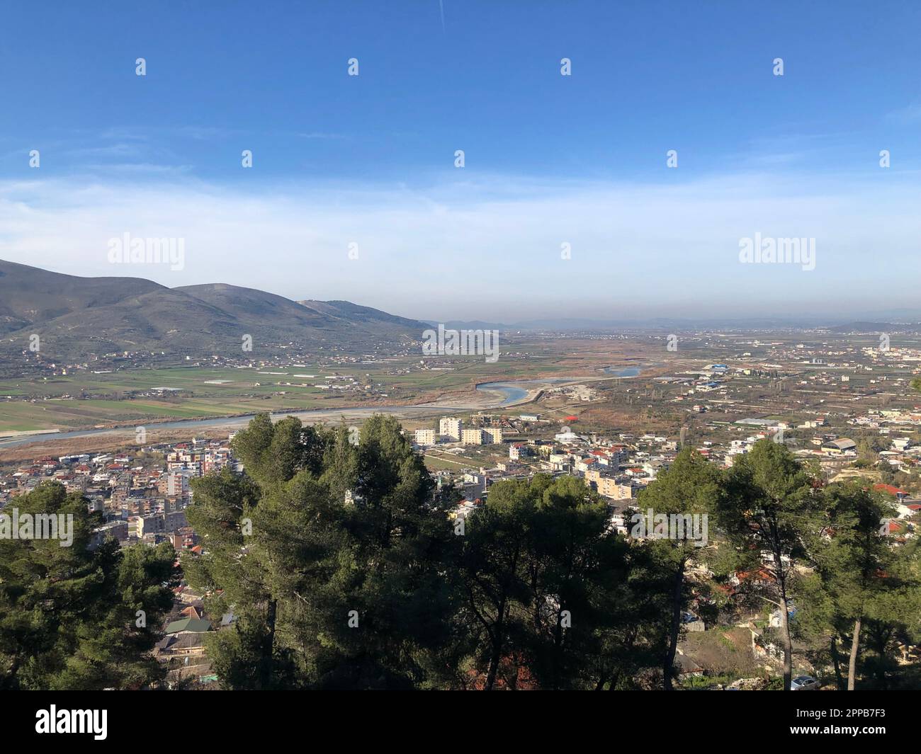A sunny cityscape featuring a stunning view of a city from a hilltop ...
