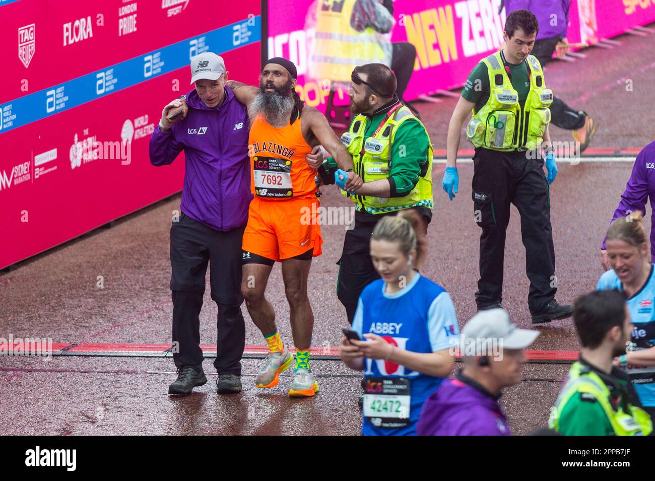 London, UK. 23 April 2023. A runner is assisted at the finish of the ...
