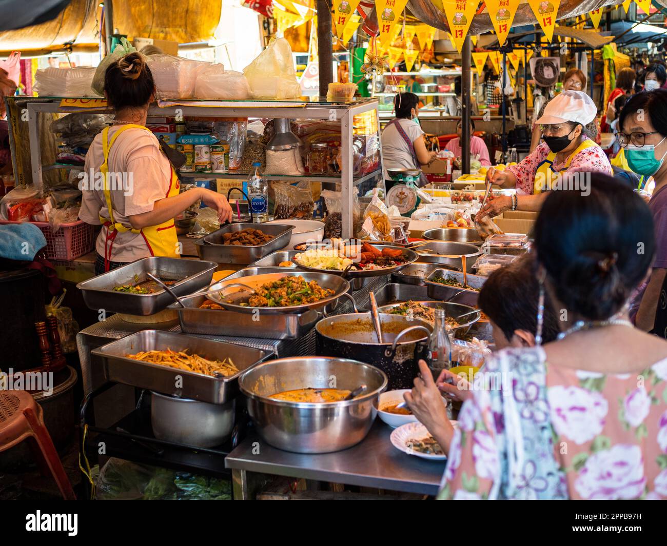 A traditional food market with many dishes and people wearing face ...