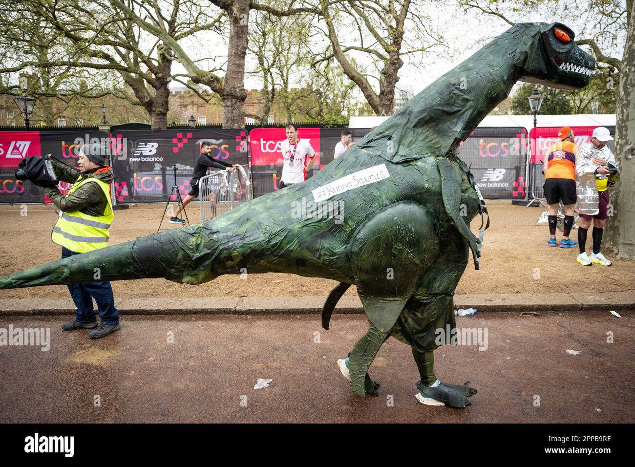 London, UK. 23 April 2023. A runner dressed as a dinosaur at the finish ...