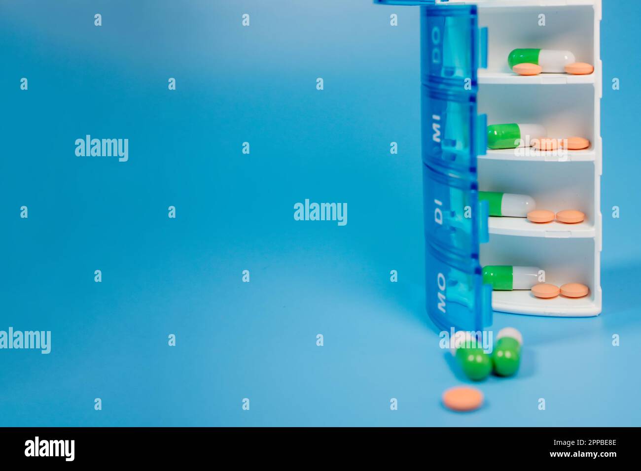 Plastic container with various pills on a blue background. Planning the ...