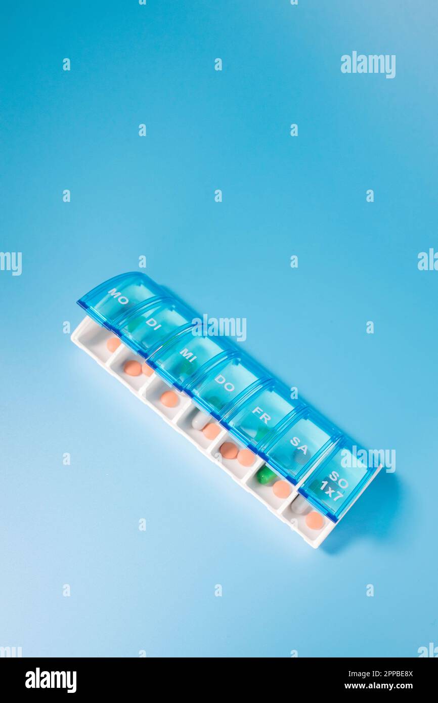 Plastic container with various pills on a blue background. Planning the ...