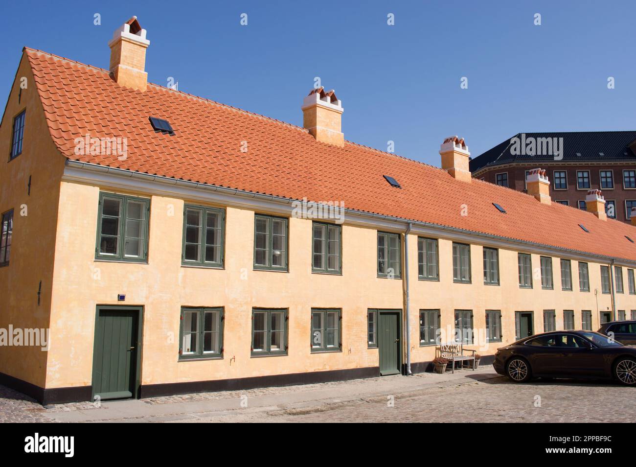 Traditional yellow terraced house with a red roof and a clear blue sky ...