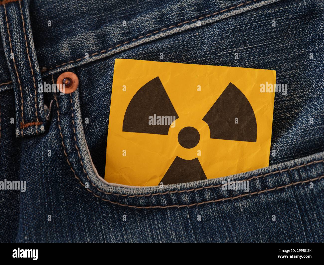 A radiation warning sign sticking out from a jeans pocket. Close up ...