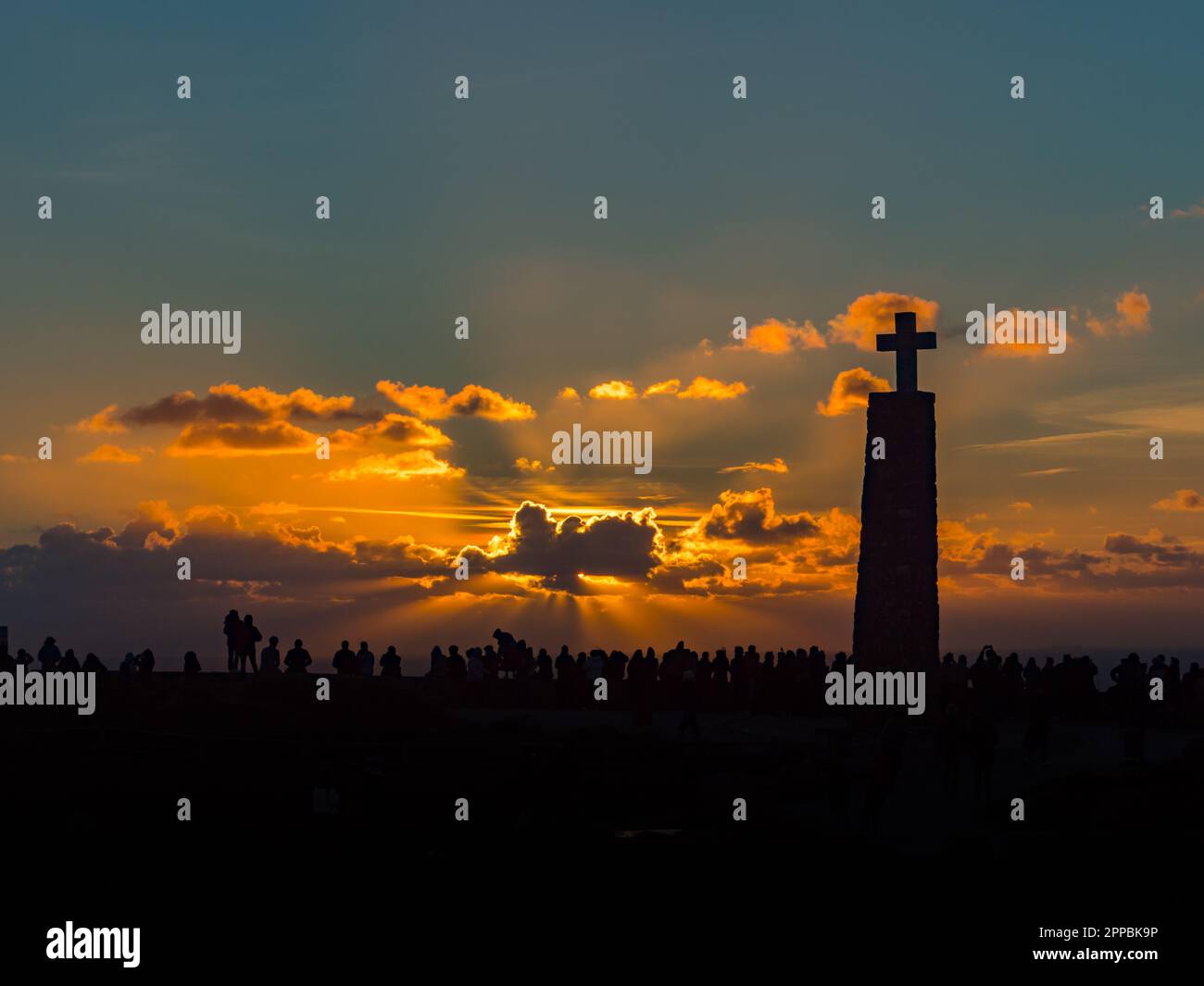 Silhouettes of people and a large cross against the backdrop of a ...
