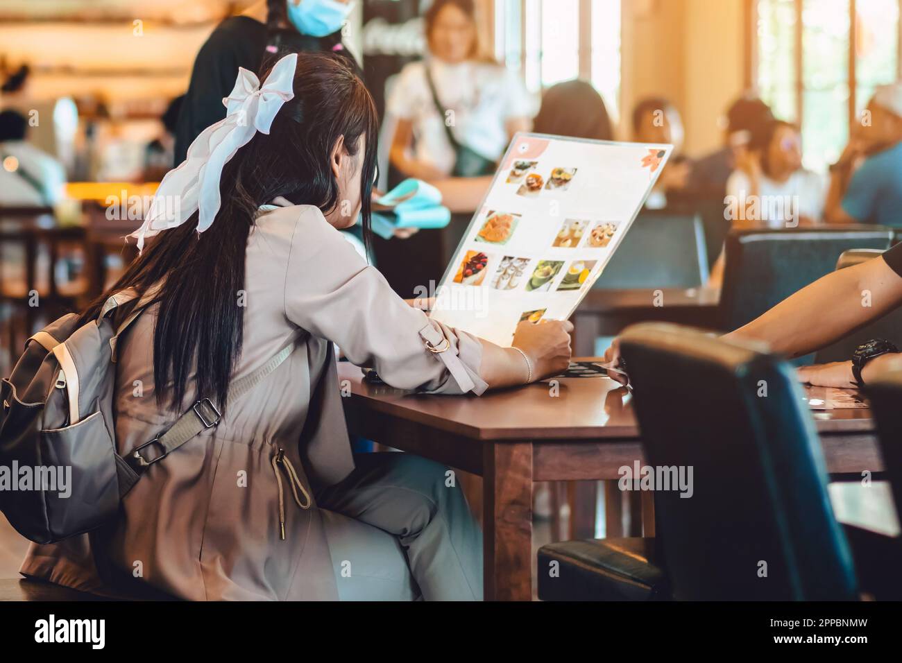 Back view of Asian young couple reading menu and choosing meal together ...