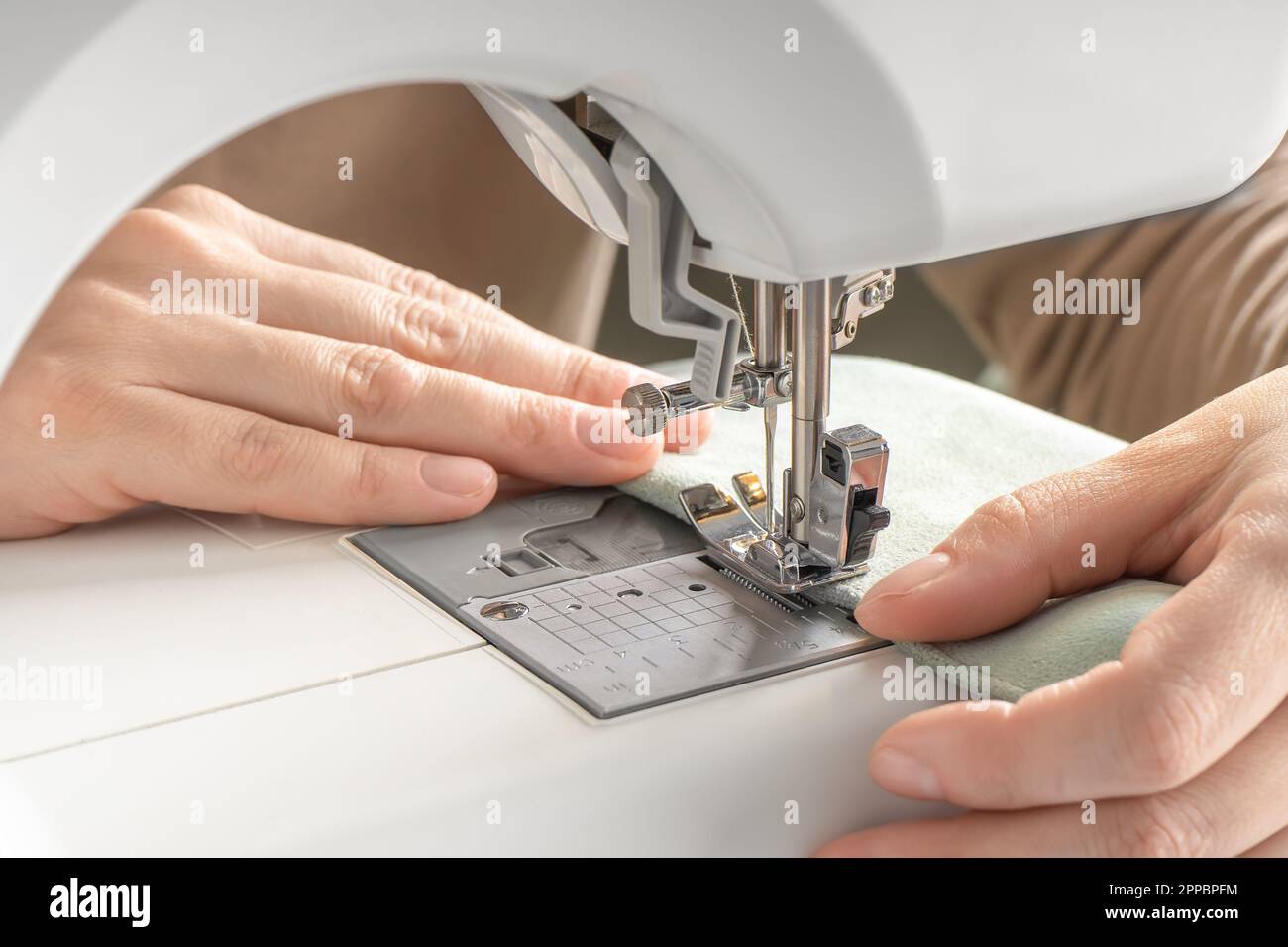Female hands stitching white fabric on modern sewing machine at ...