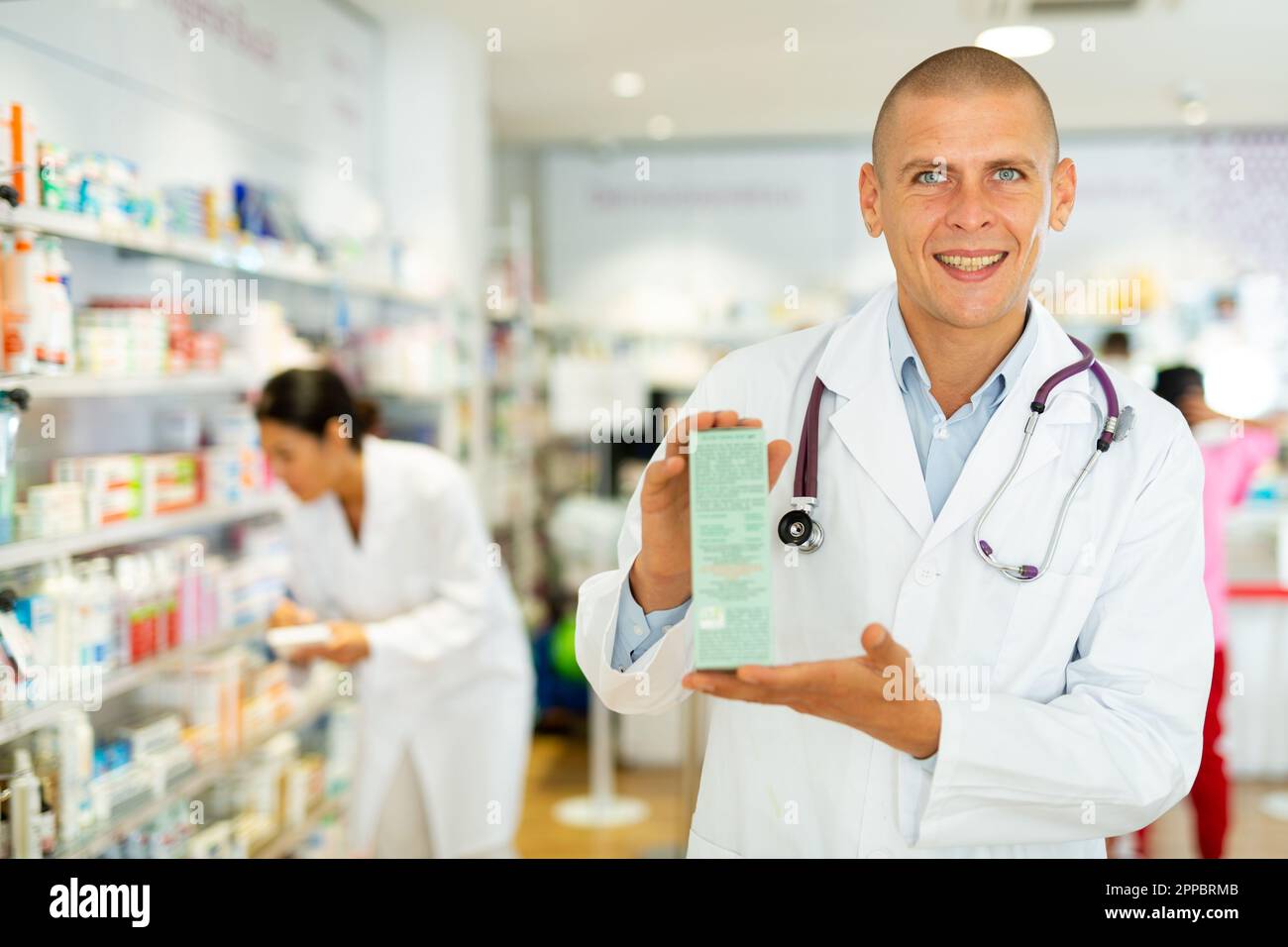 Male doctor with pharmaceutical package standing in drugstore Stock ...