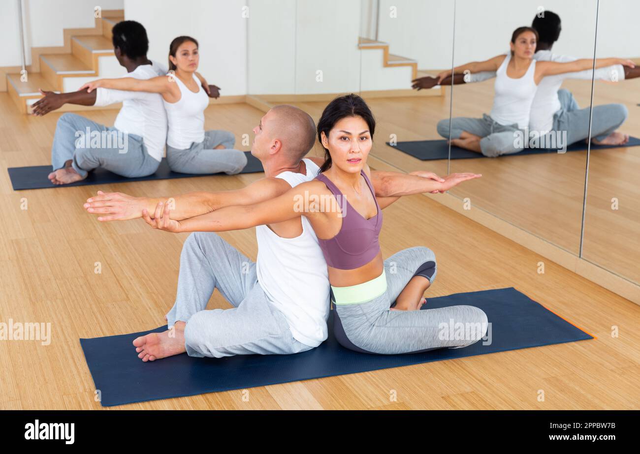 Couples practicing yoga with partner at studio Stock Photo - Alamy