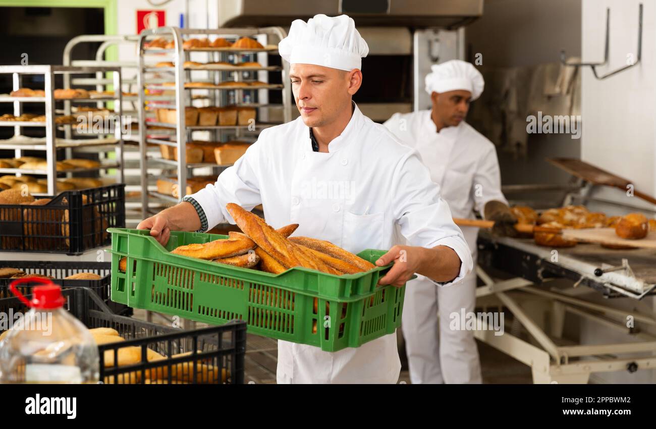 man in chefs uniform with bread in tray in bakery Stock Photo - Alamy