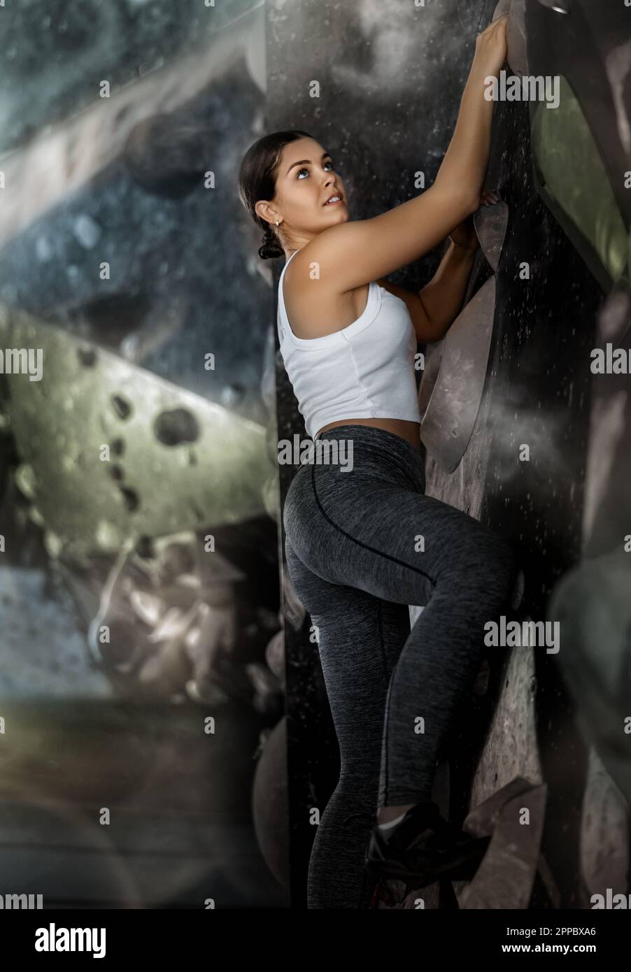 Female fitness climber training at bouldering gym. Young woman rise up ...
