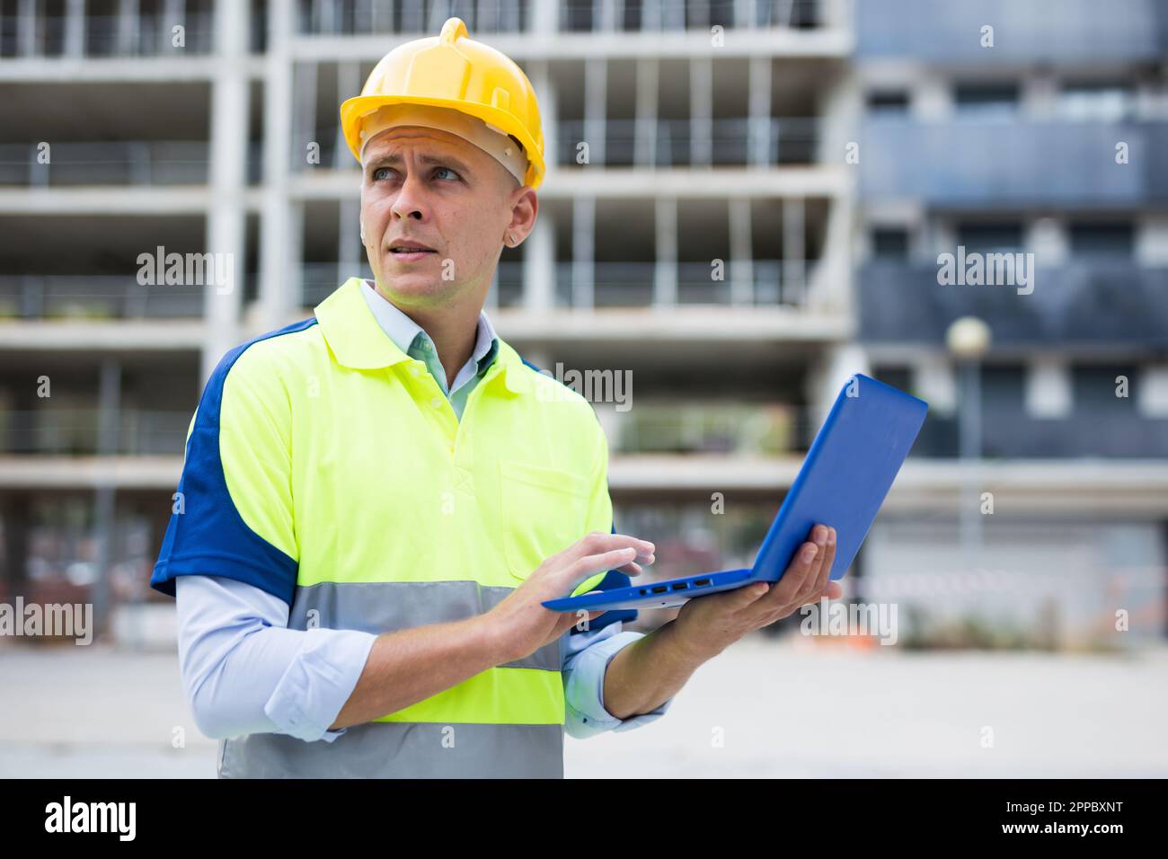 Engineer with laptop in construction site Stock Photo - Alamy