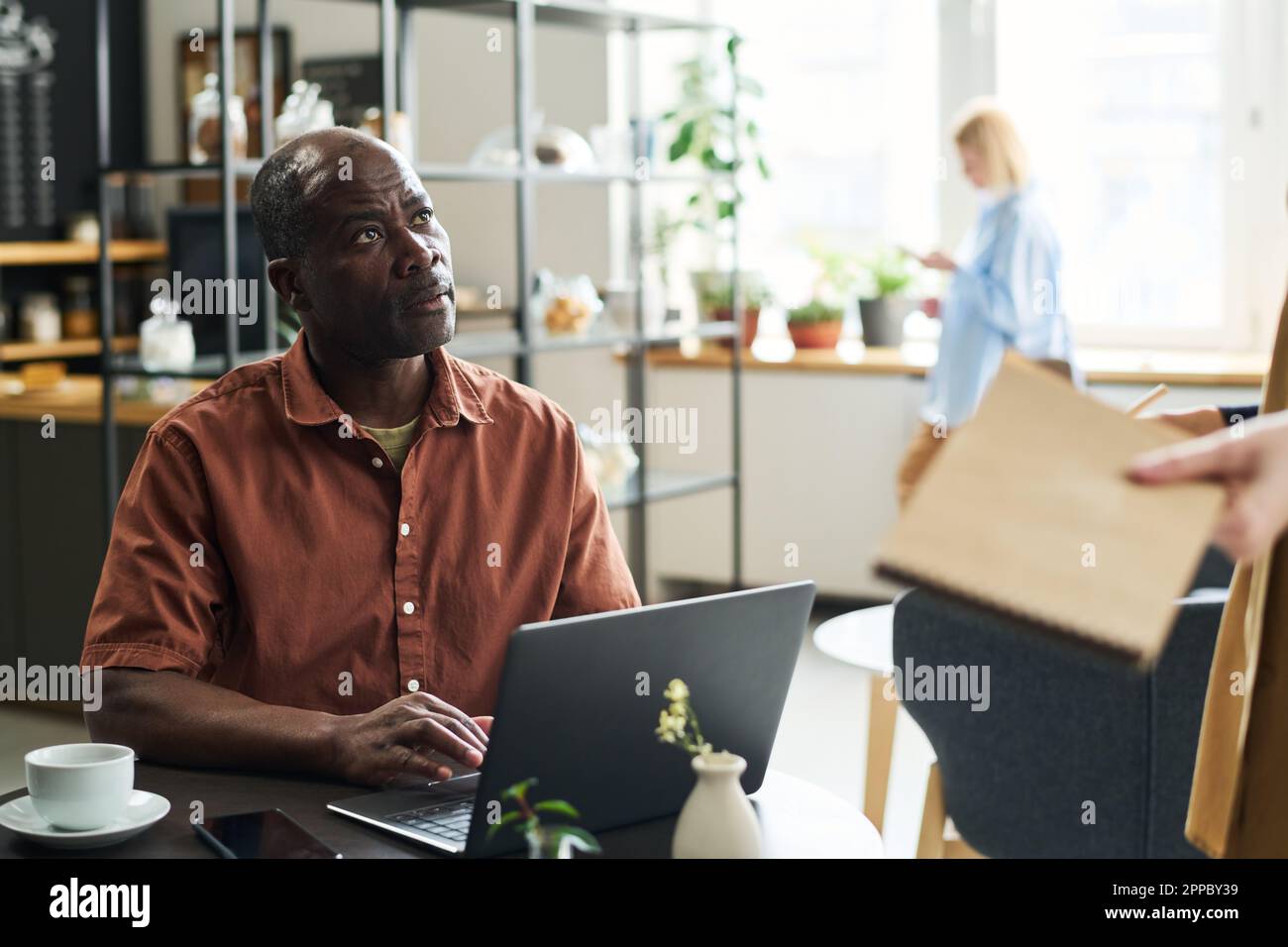 Mature businessman looking at waitress with notepad while sitting by ...