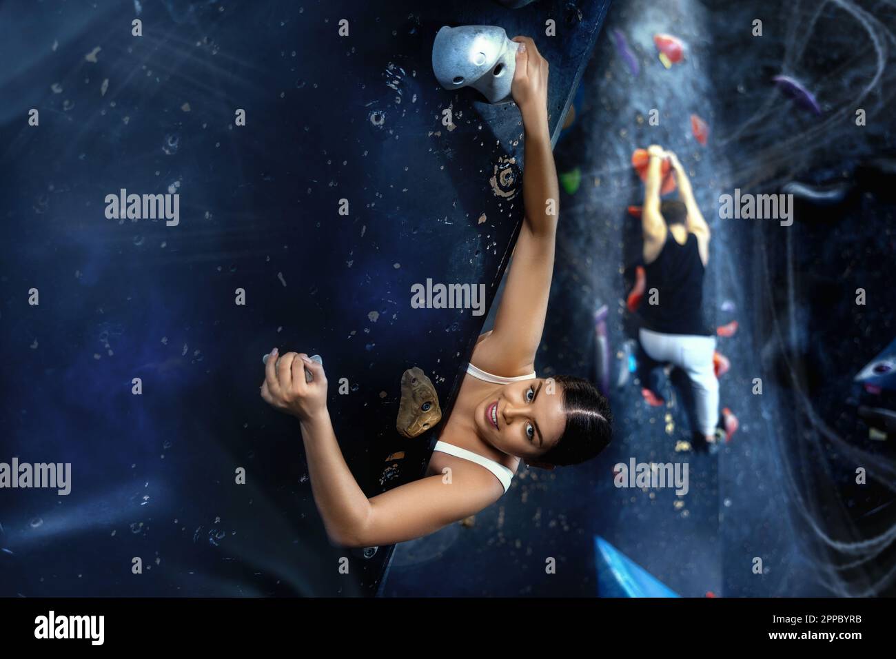 Female fitness climber training at bouldering gym. Young woman rise up ...