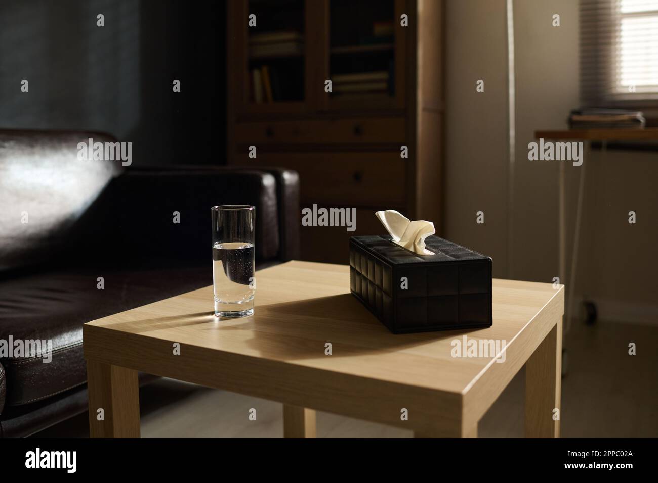Small wooden square table with glass of pure water and black box ...