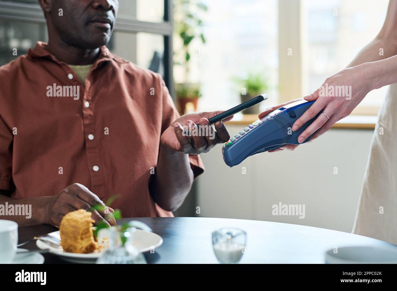Close-up of hands of waitress holding payment terminal in front of ...