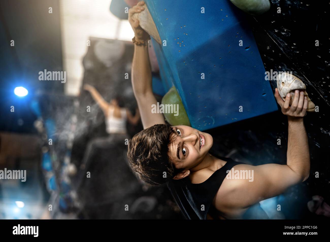 young muscular male sportsman climbing black wall for bouldering in gym ...